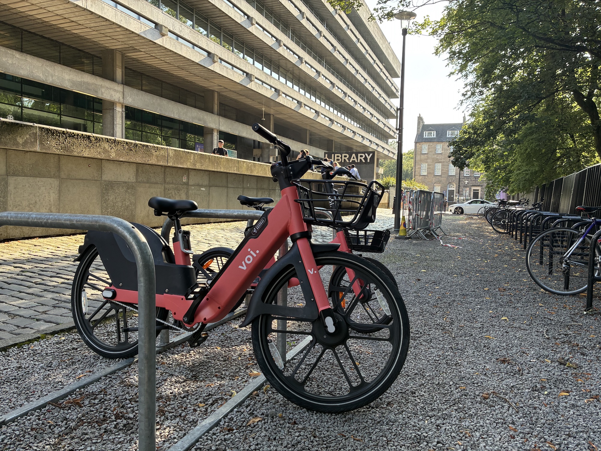 A red e-bike is parked in a bike rack outside the Edinburgh Library