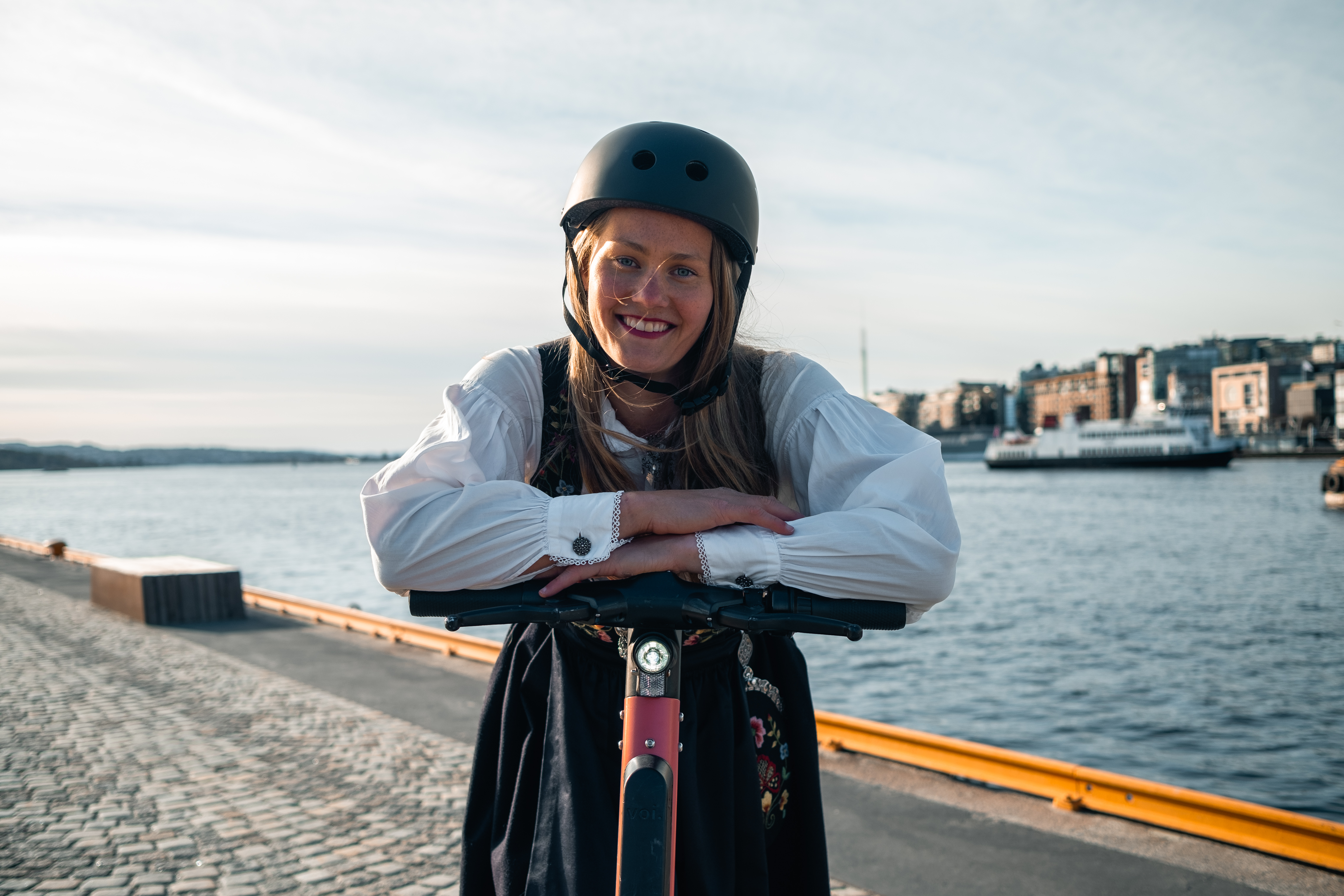 A woman in a traditional Norwegian dress and a helmet is leaning over ...